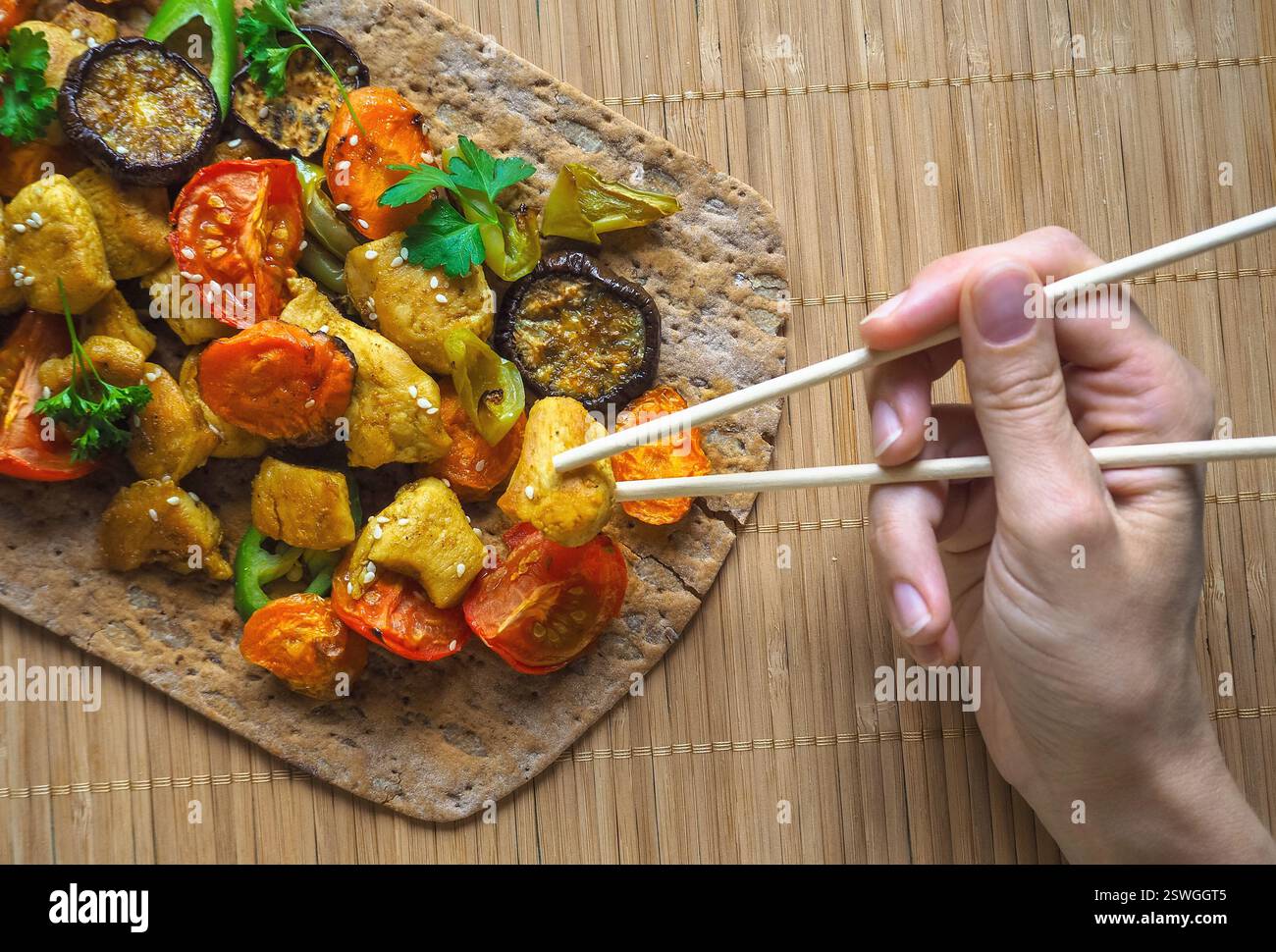 The hand holding chopsticks a piece of chicken. Grilled baked ...