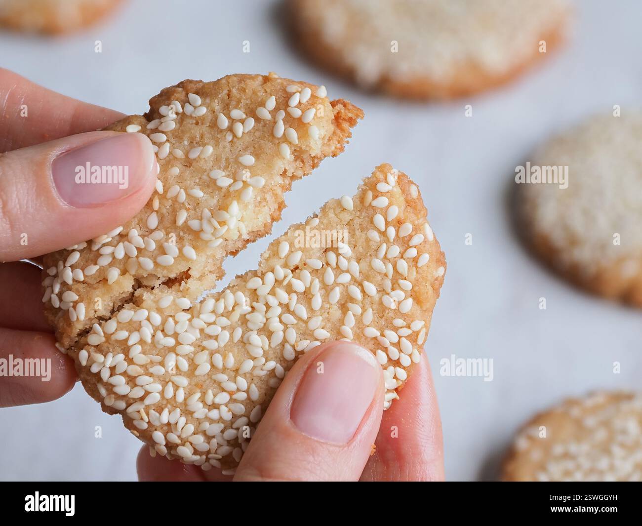 Hand breaks fresh delicious sesame cookies Stock Photo - Alamy