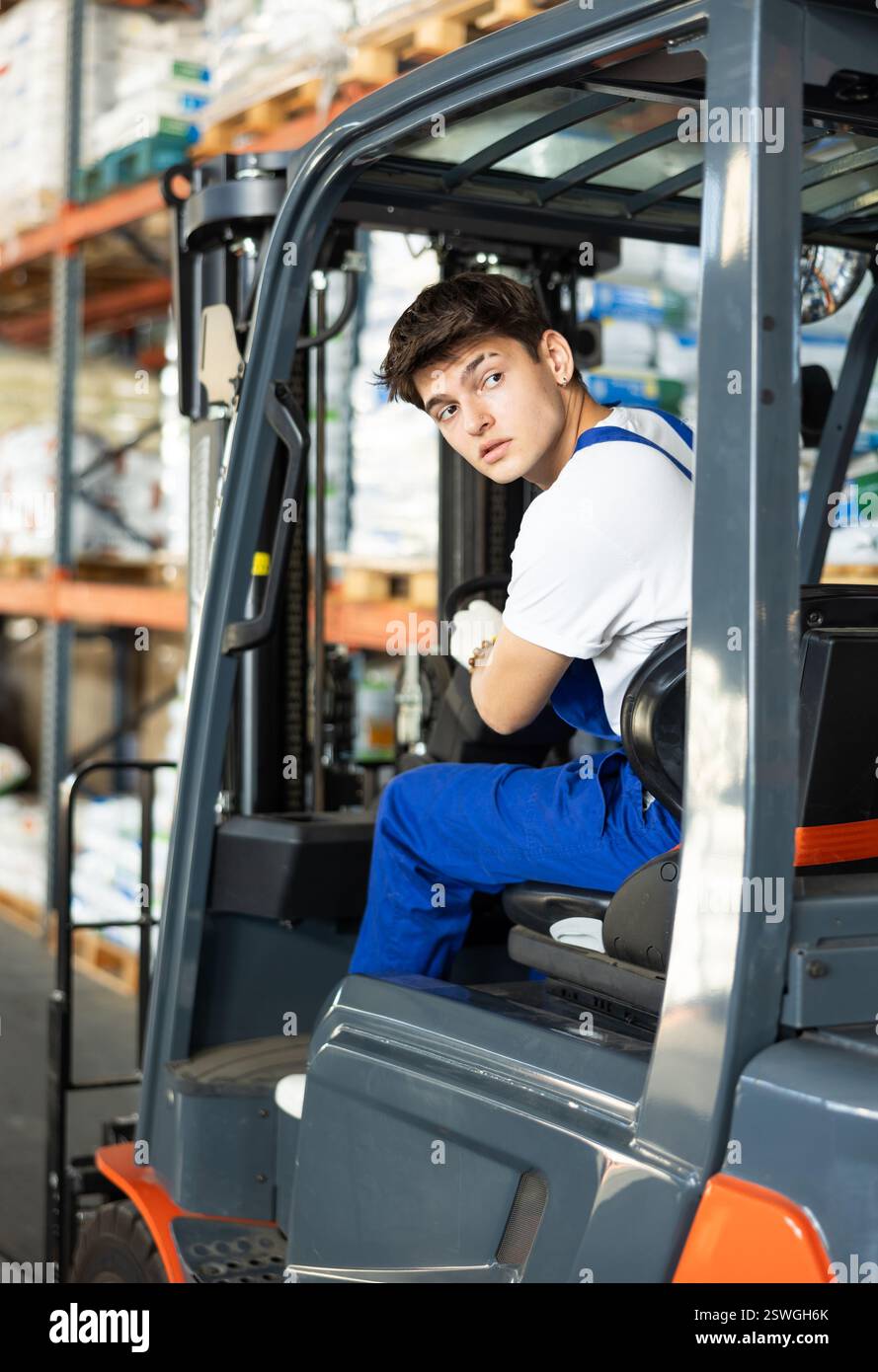 Young guy worker works on loader in warehouse Stock Photo - Alamy