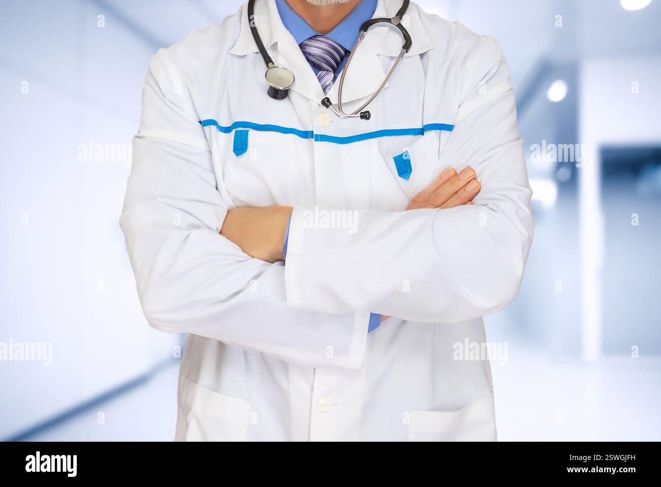 A healthcare worker stands with arms crossed in a modern hospital ...