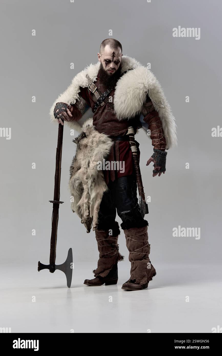 Man dressed as Viking warrior in medieval fur cloak and rugged armor ...
