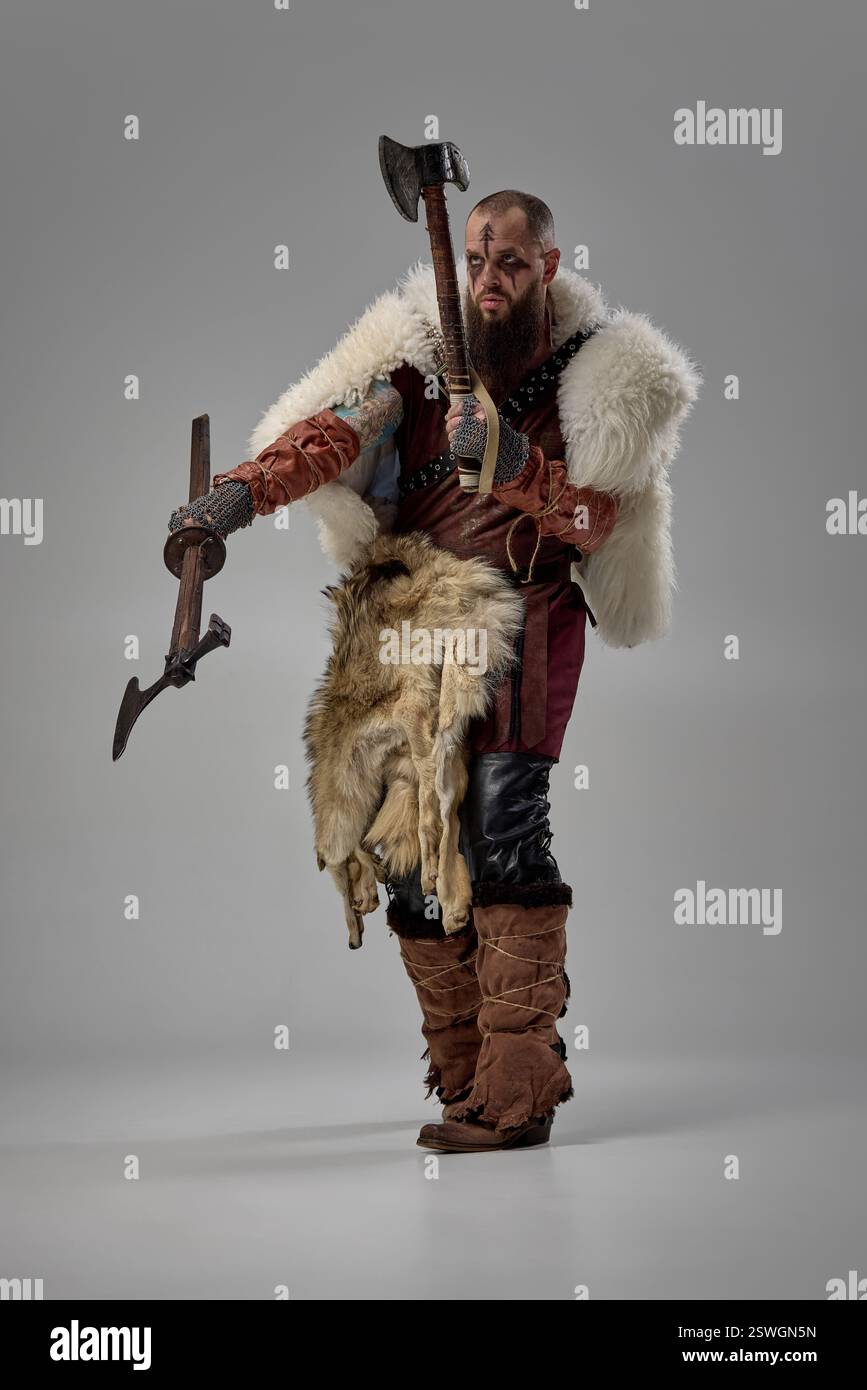 Warrior gripping two axes with intense gaze, man dressed in armor and ...