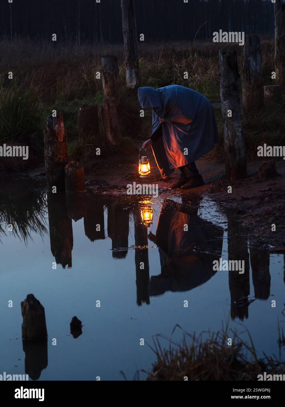 Bent man holding the old lamp outdoors near the lake. Hand holds a ...