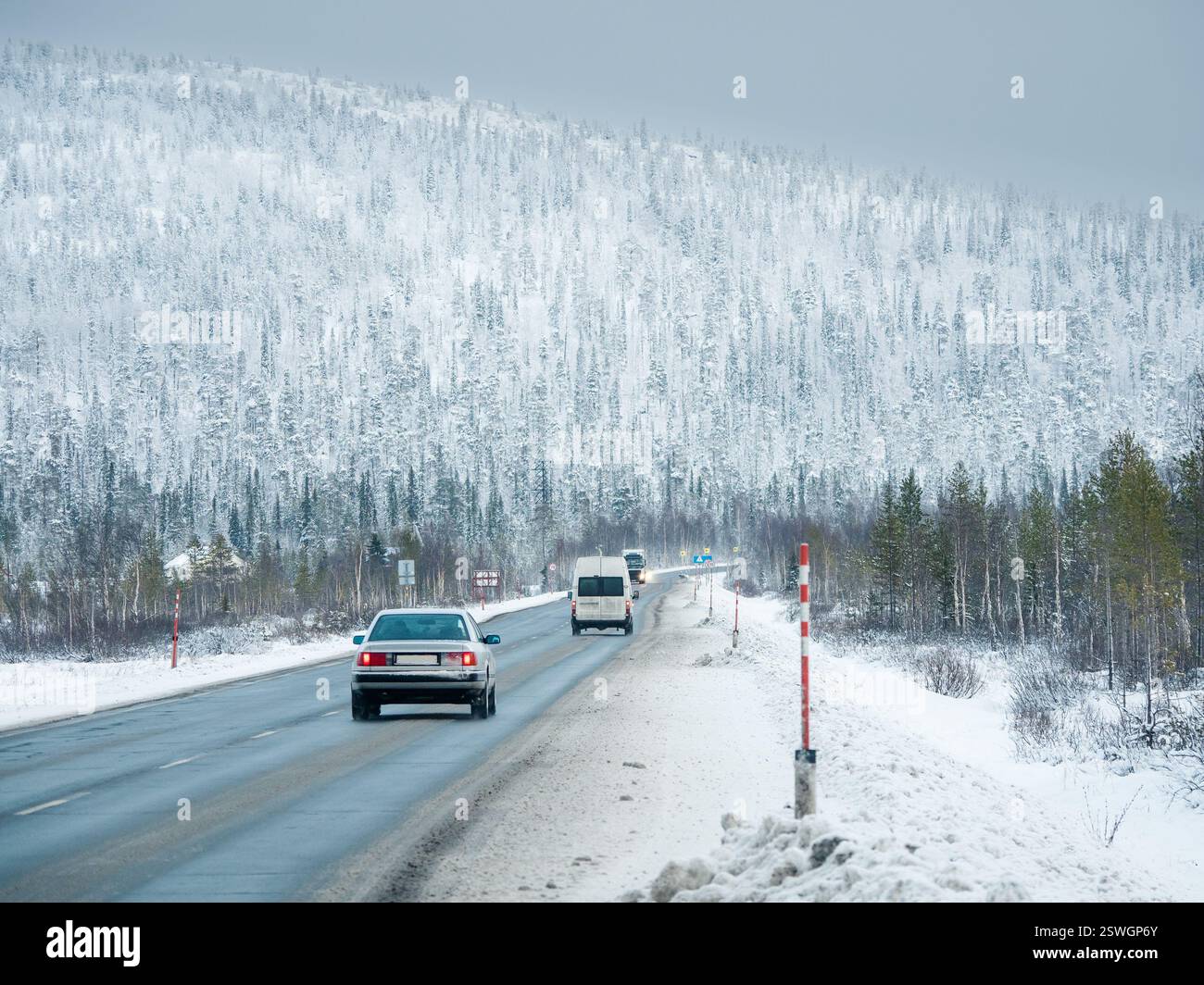 Polar traffic of cars on a slippery road among snow-covered hills Stock ...