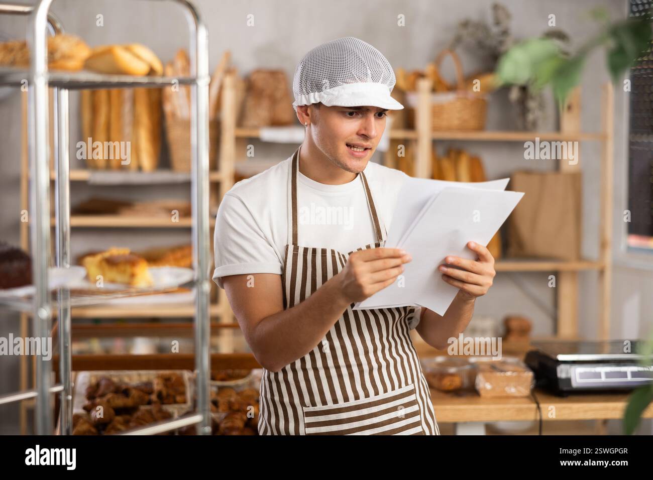 Frustrated male owner of bakery reads documents and reflects, makes ...