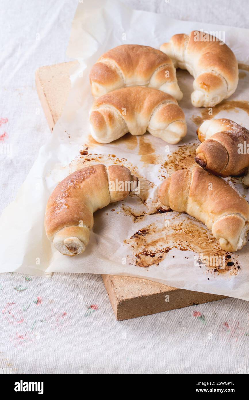 Fresh homemade baked crescent rolls on baking paper and oven stone over ...