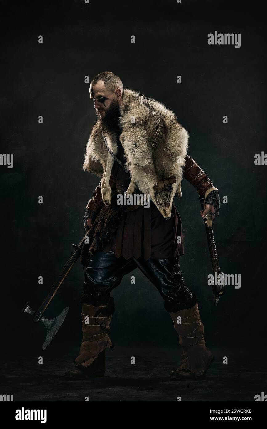 Viking warrior standing in battle stance gripping axe and sword ...