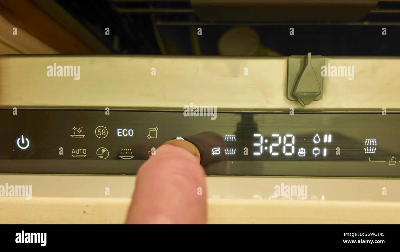 A male finger on the control panel of the dish washer. Switching ...