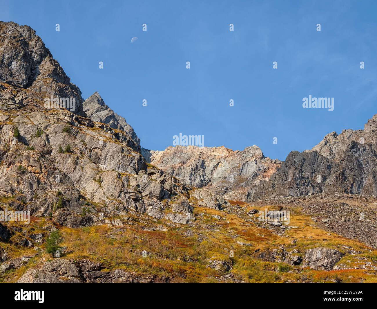 Bright mountain landscape with sharp rocks above yellow slope under ...