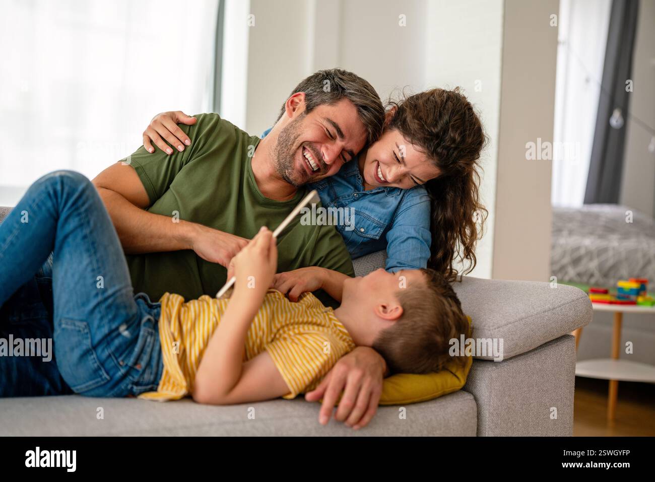 Parents and child relaxing at home with computer watching funny ...