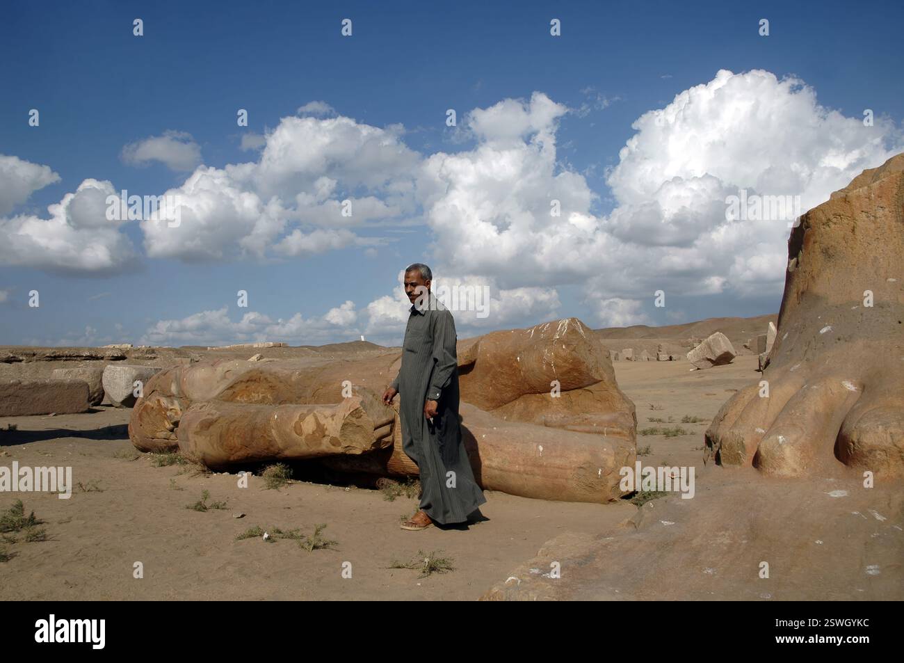 An Egyptian man stands by sculptural fragments, recovered from the ...