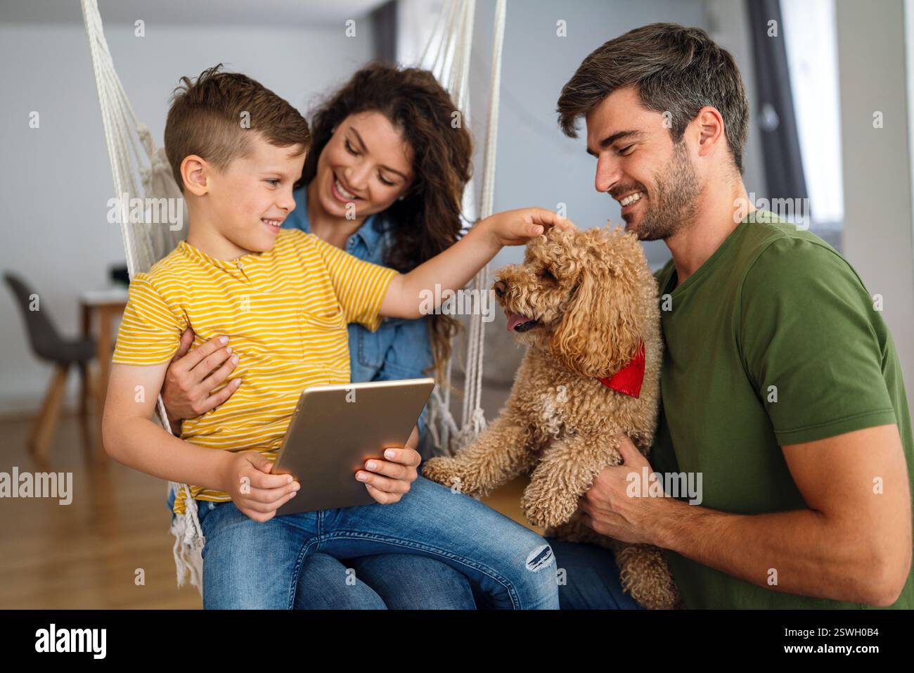 Happy family with kid having fun using tablet together, parents and child laughing relaxing at ...