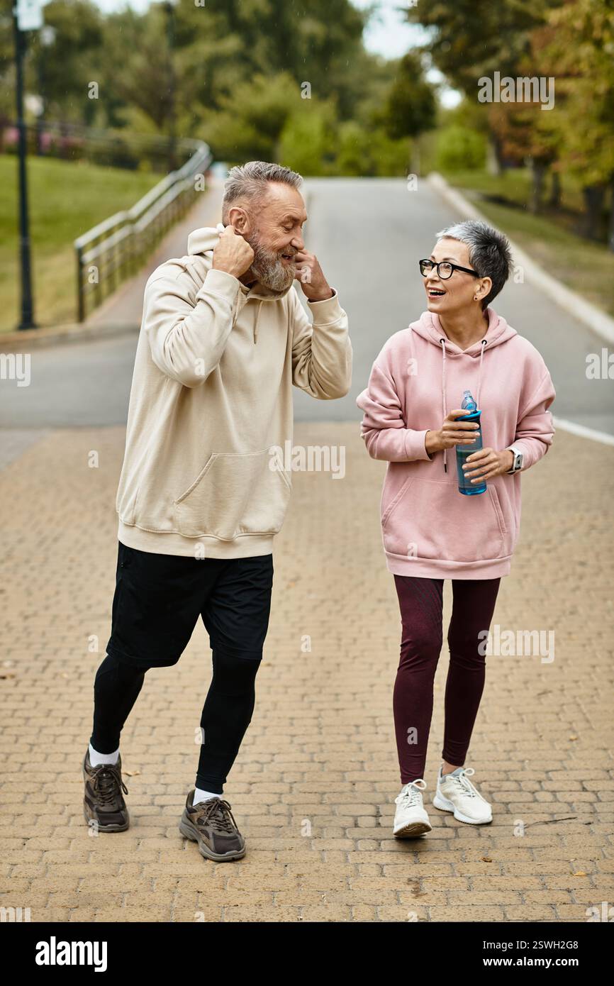 Mature couple shares laughter and love during a relaxing walk in a beautiful park setting Stock ...