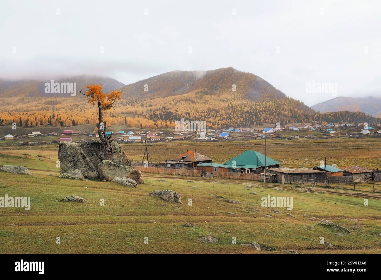 Outskirts of the village in autumn. Split in half large granite boulder ...