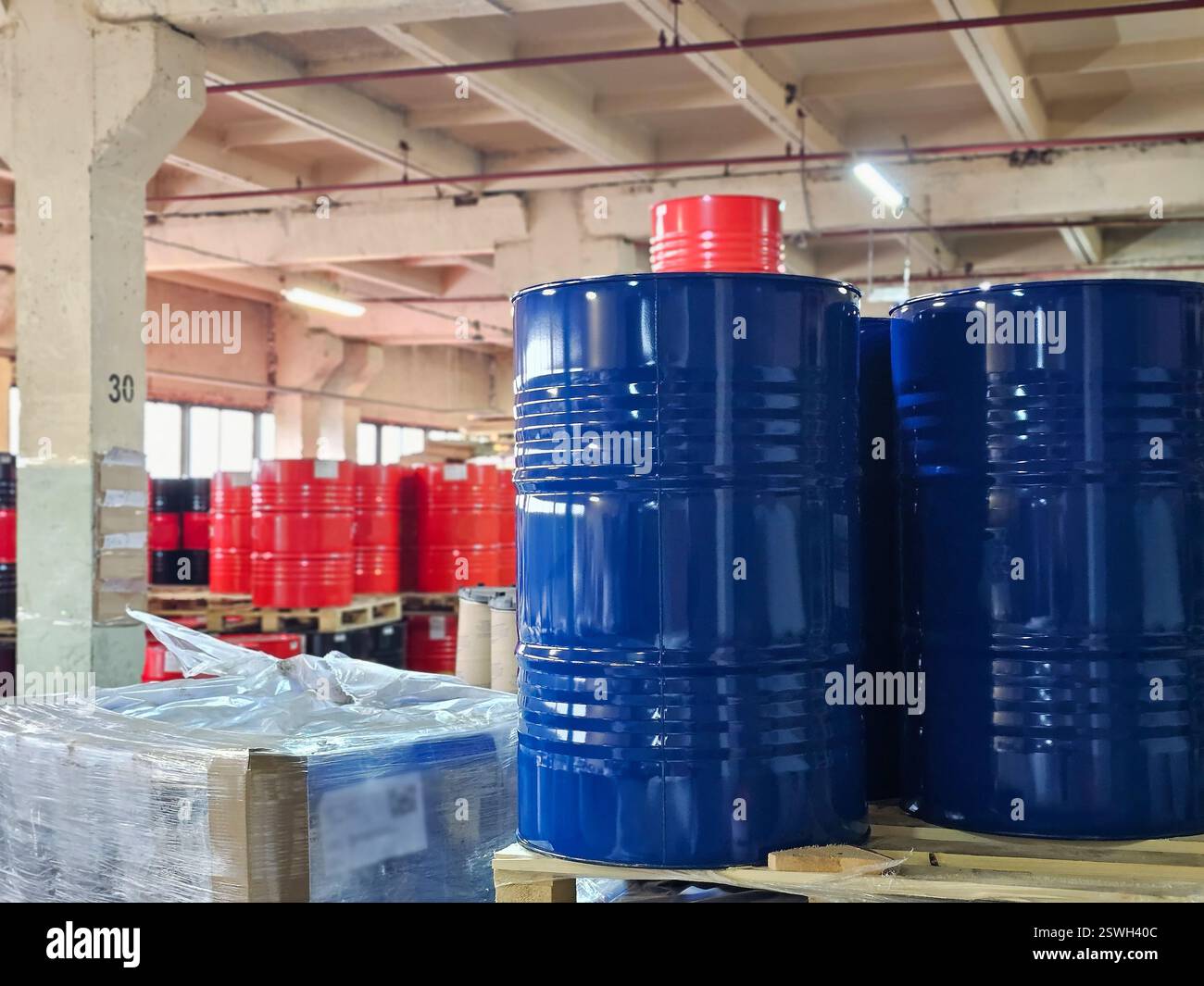 Metal blue and red barrel in the warehouse, 200-liter chemical barrels are arranged on wooden ...