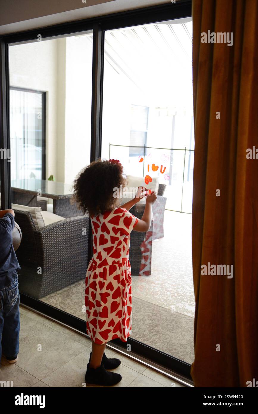 Children decorating a window with heart-shaped gel letters Stock Photo ...