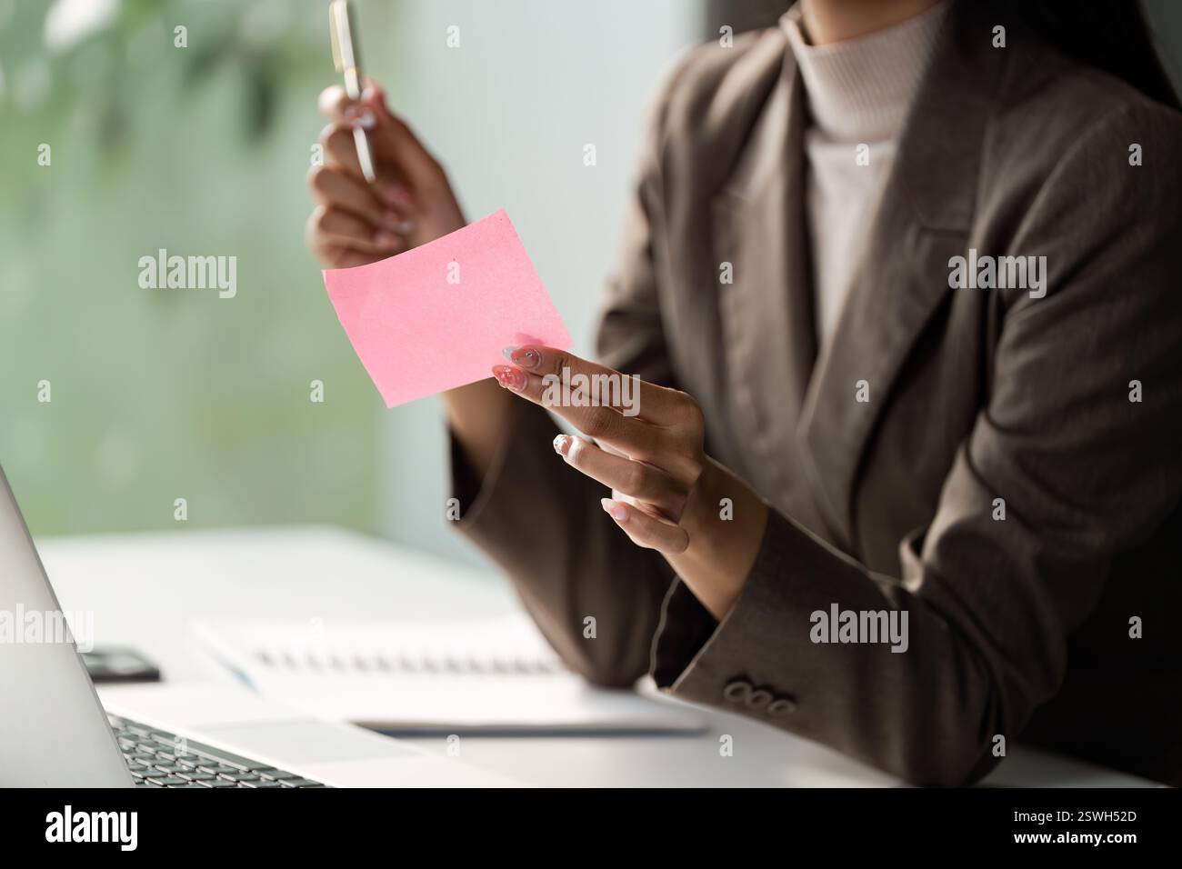 Professional woman reviewing sticky notes at a modern office desk ...