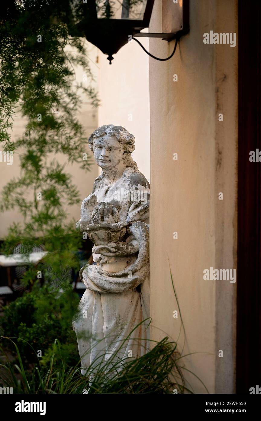 Weathered stone statue in a charming courtyard with greenery Stock ...