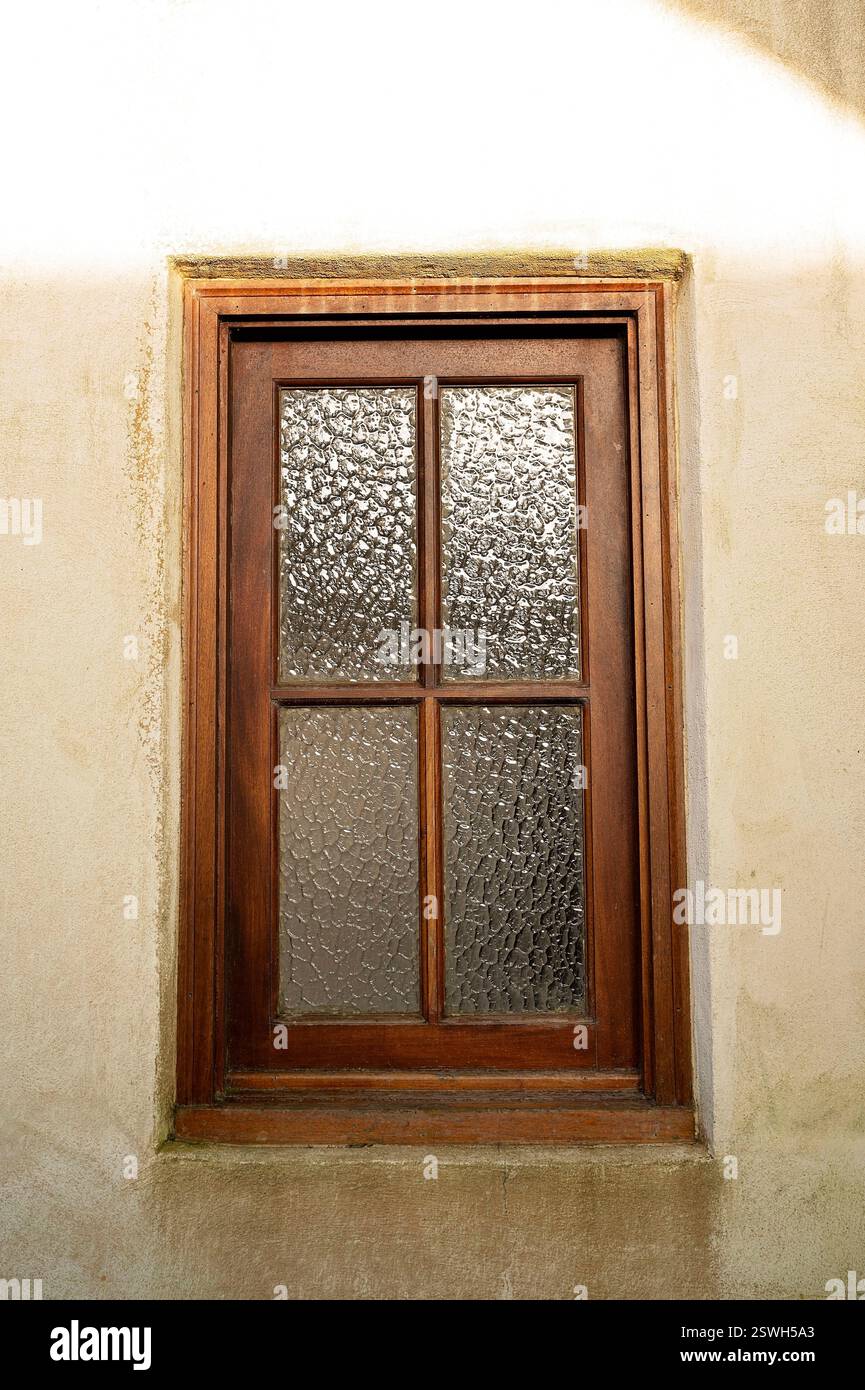 Wooden-framed window with textured glass set in a stucco wall Stock ...