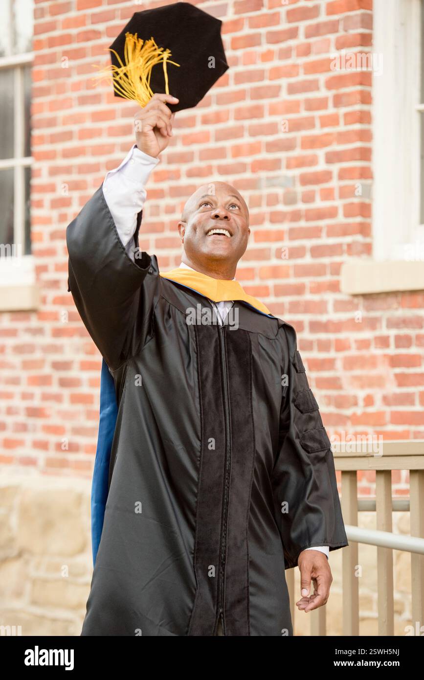 Graduate joyfully raising cap in celebration of achievement Stock Photo ...