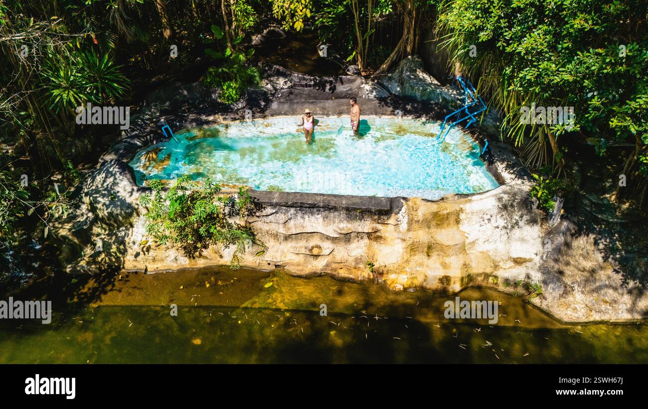 Two people enjoy a serene day in a secluded natural pool, embraced by ...