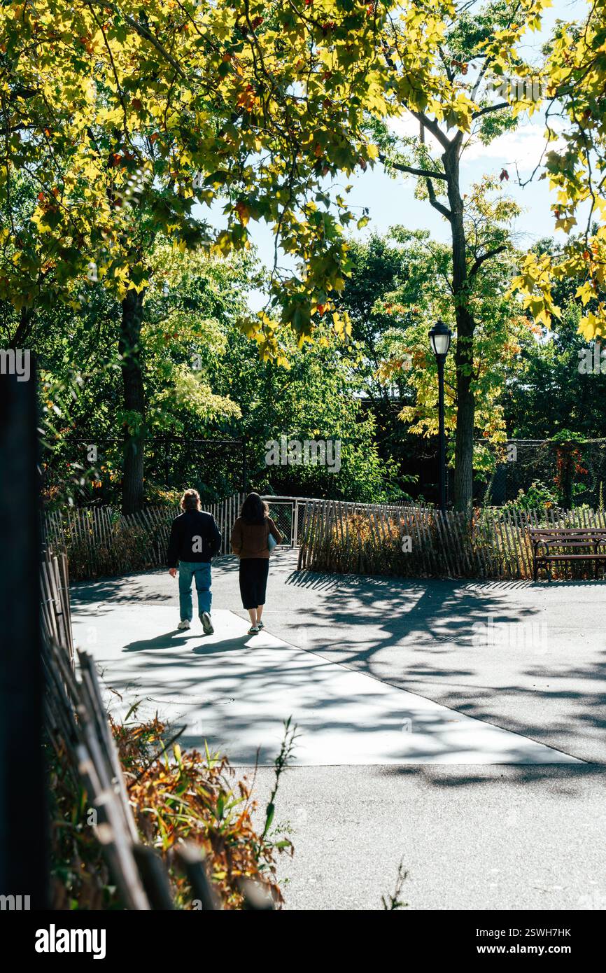 Two people stroll along a path in Squibb Park Bridge, surrounded Stock ...