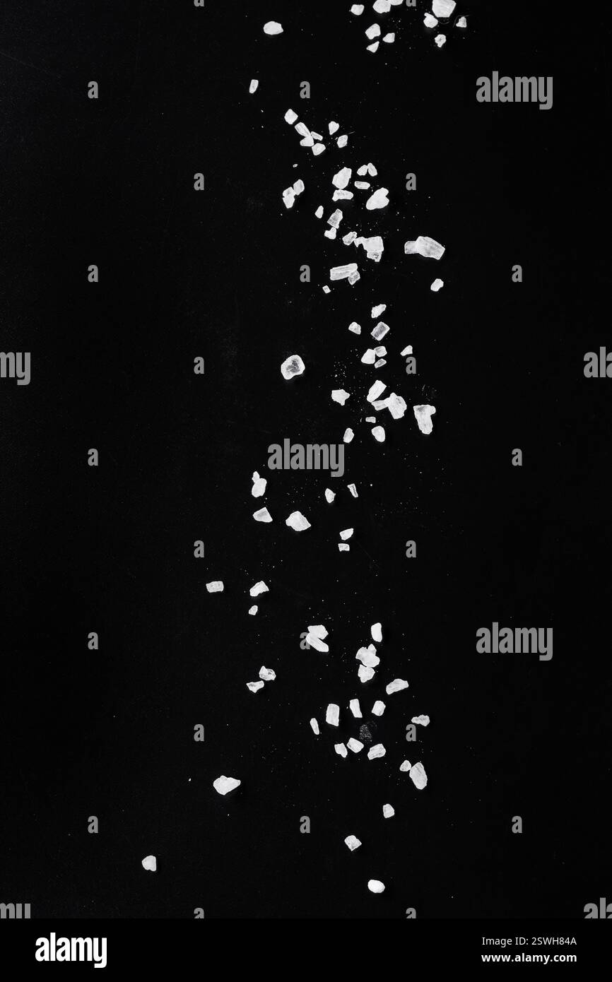Sifting sea salt over black background Stock Photo - Alamy