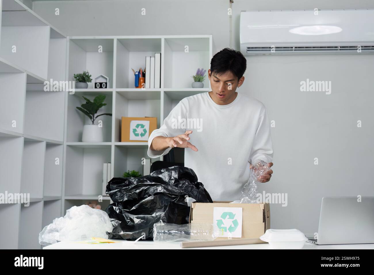 Young man sorting recyclable materials in eco-friendly workspace ...