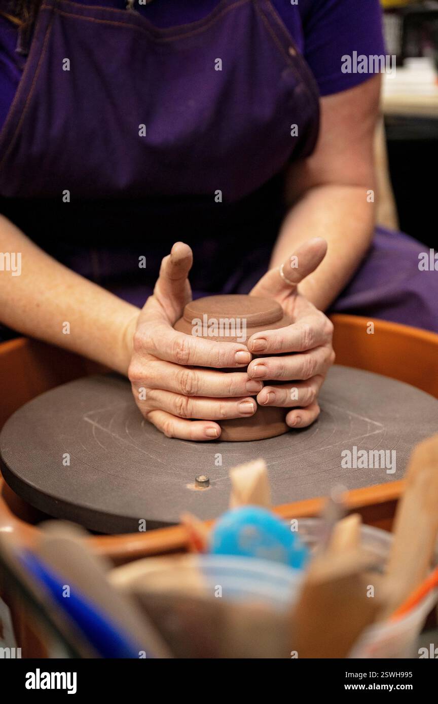Artisan shaping clay on a pottery wheel in a ceramics studio Stock ...