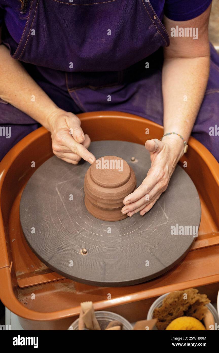 Artisan shaping clay on a pottery wheel in a ceramics studio Stock ...