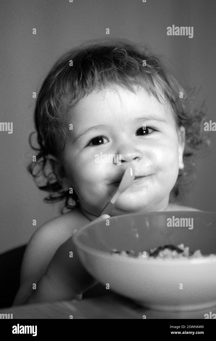 Cutr baby child eating himself with a spoon Stock Photo - Alamy