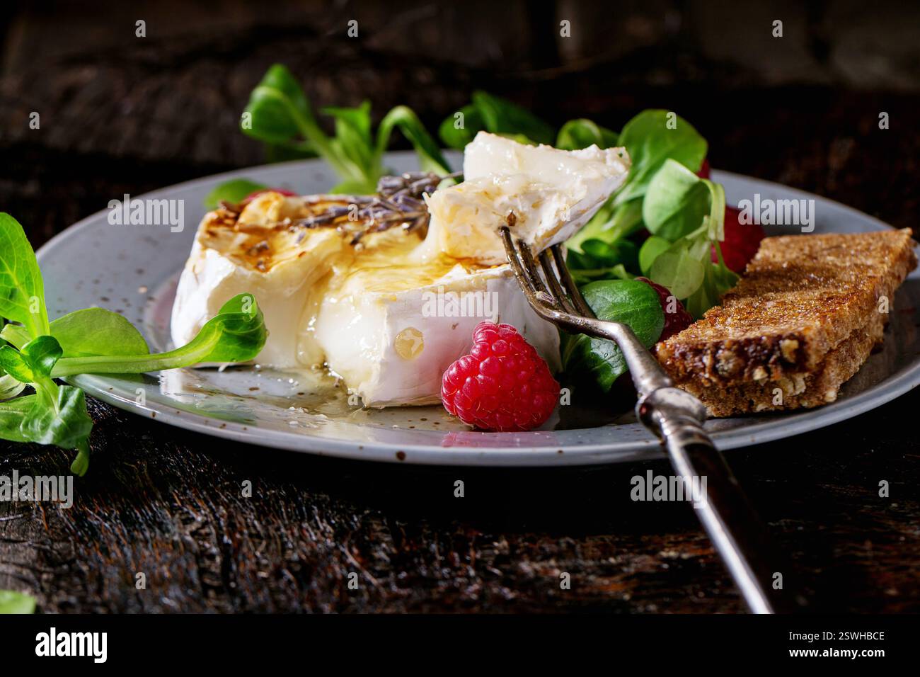 Baked Goat cheese with honey and raspberries Stock Photo - Alamy