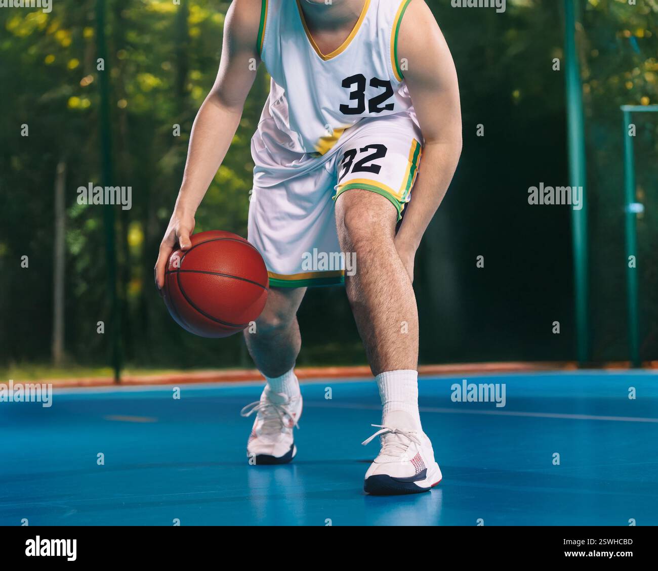 Adult male basketball player bouncing basketball at outdoor court ...