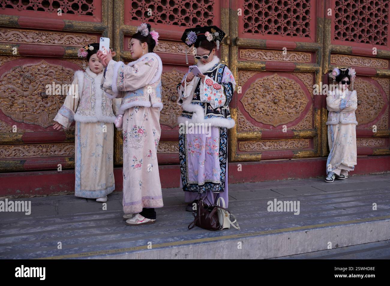 Visitors dressed in traditional costumes pose for photos at the ...