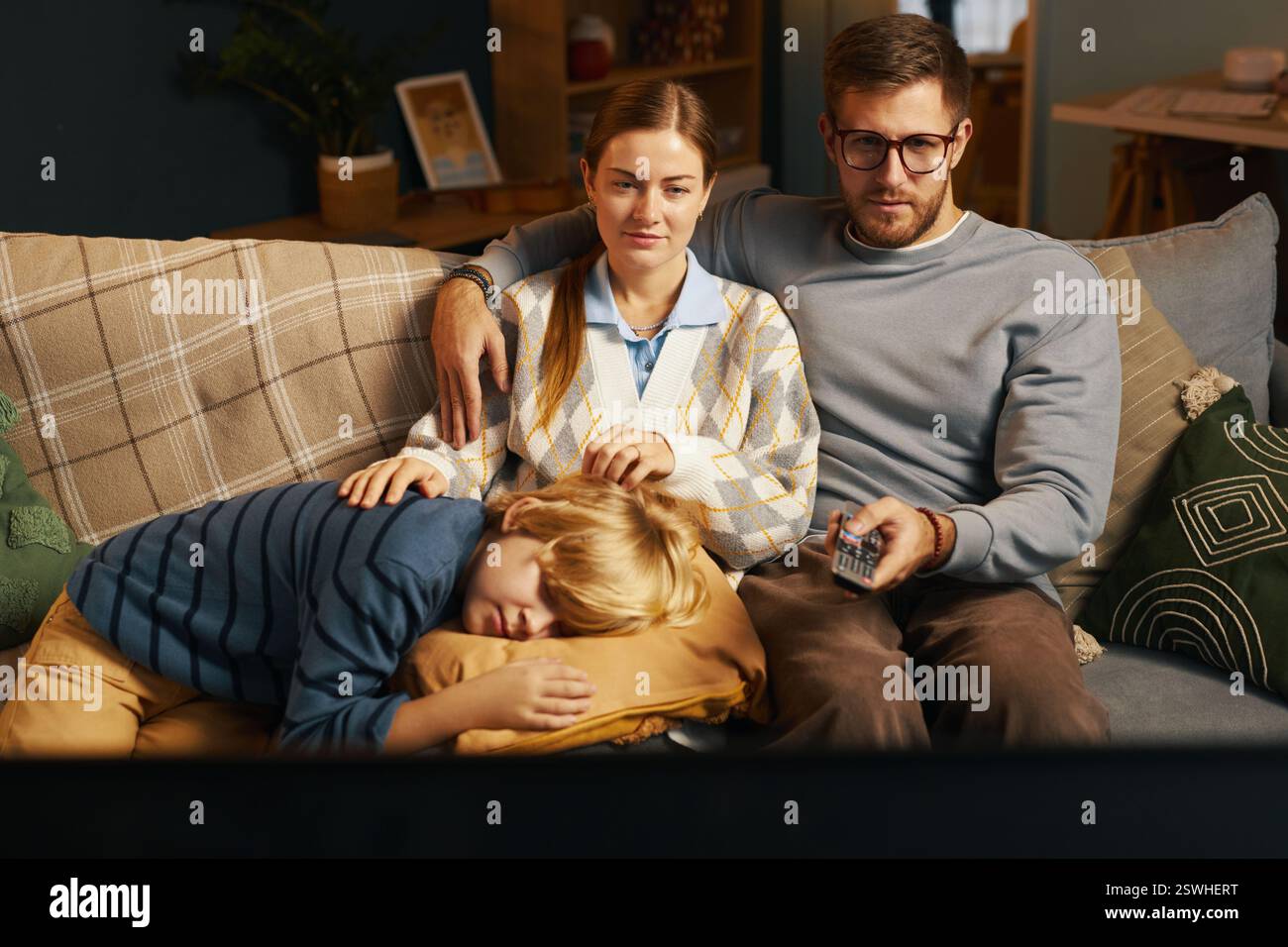 Family sitting on comfortable sofa while child rests, parents relaxing ...