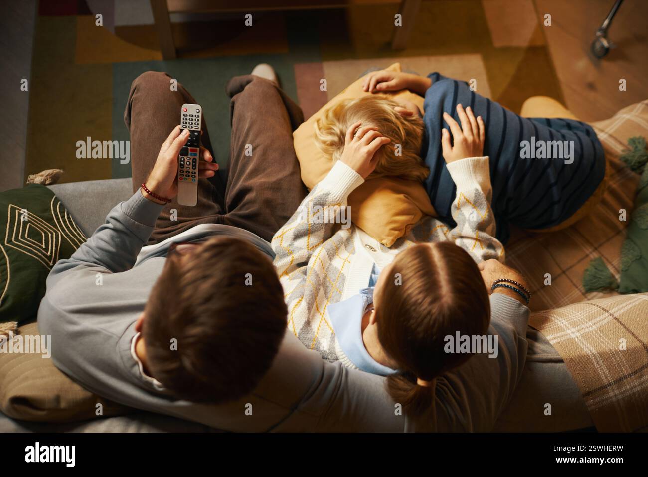 Top-view image showing family members relaxing on couch together ...