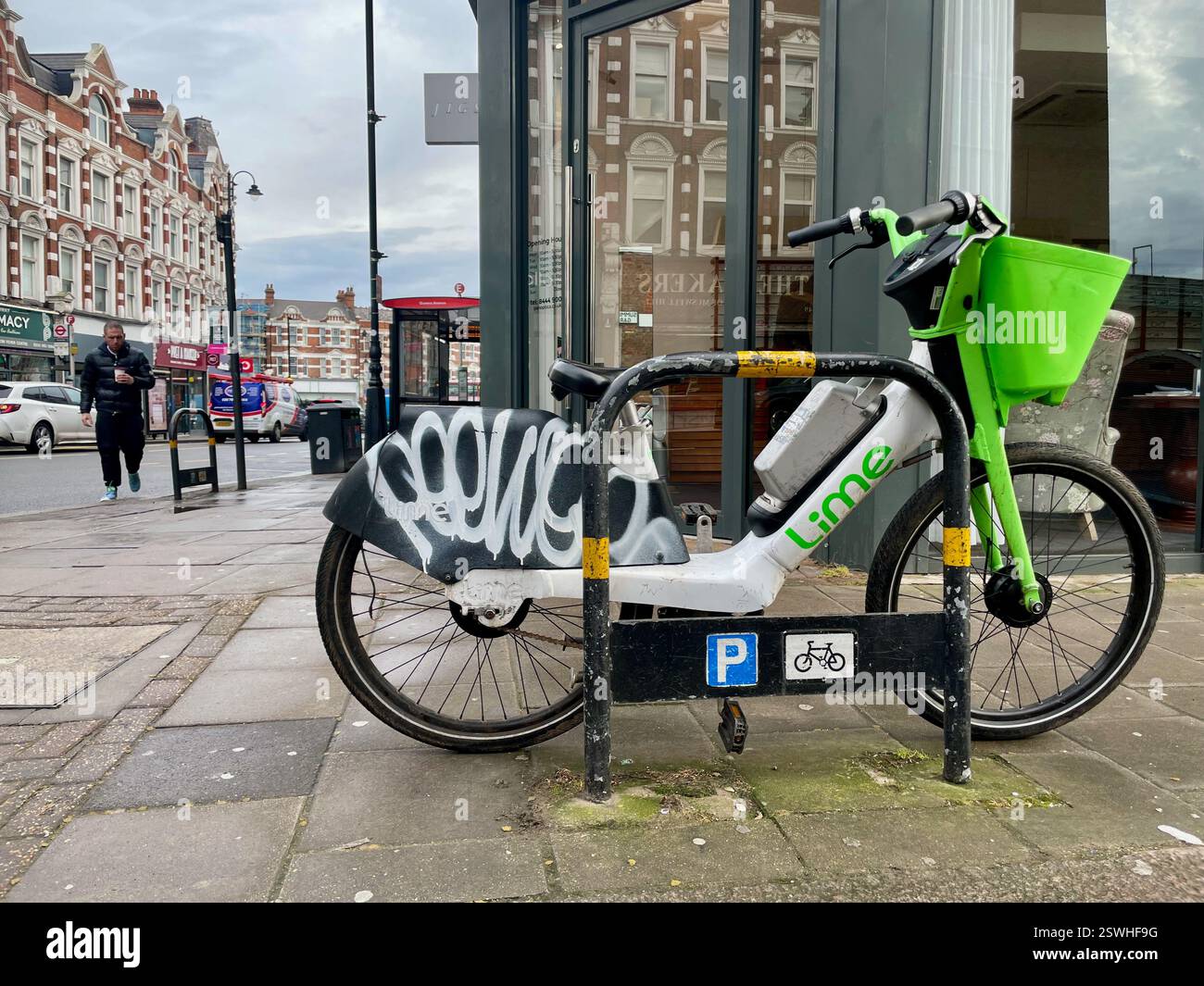 a rentable for hire lime bike covered in graffiti parked on a pavement ...