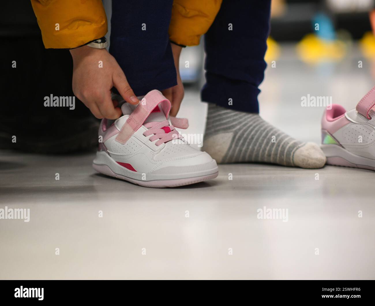 Close-up of hands fastening velcro strap on child's white shoe with ...