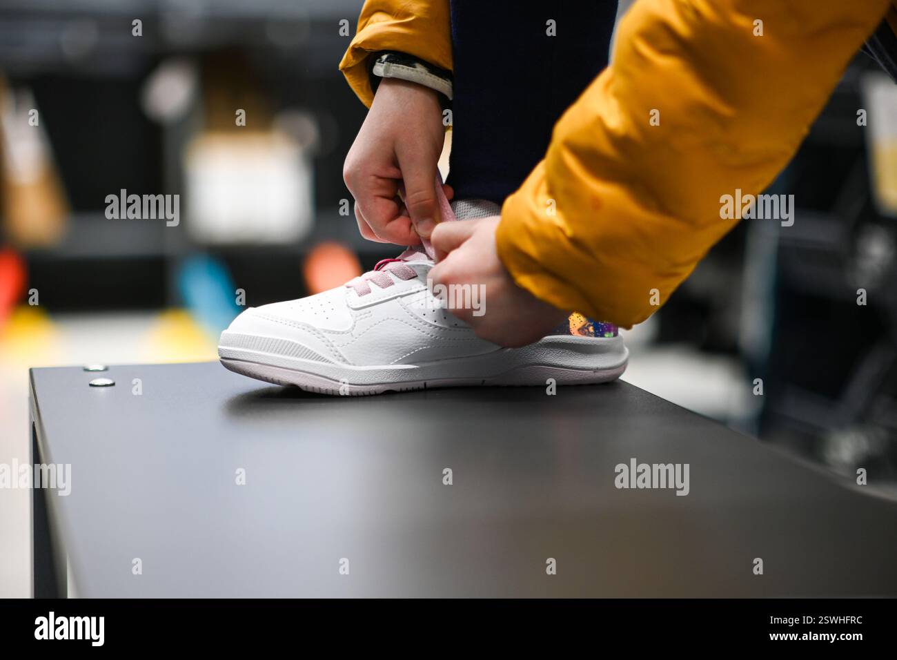 Close-up of hands fastening velcro strap on child's white shoe with ...