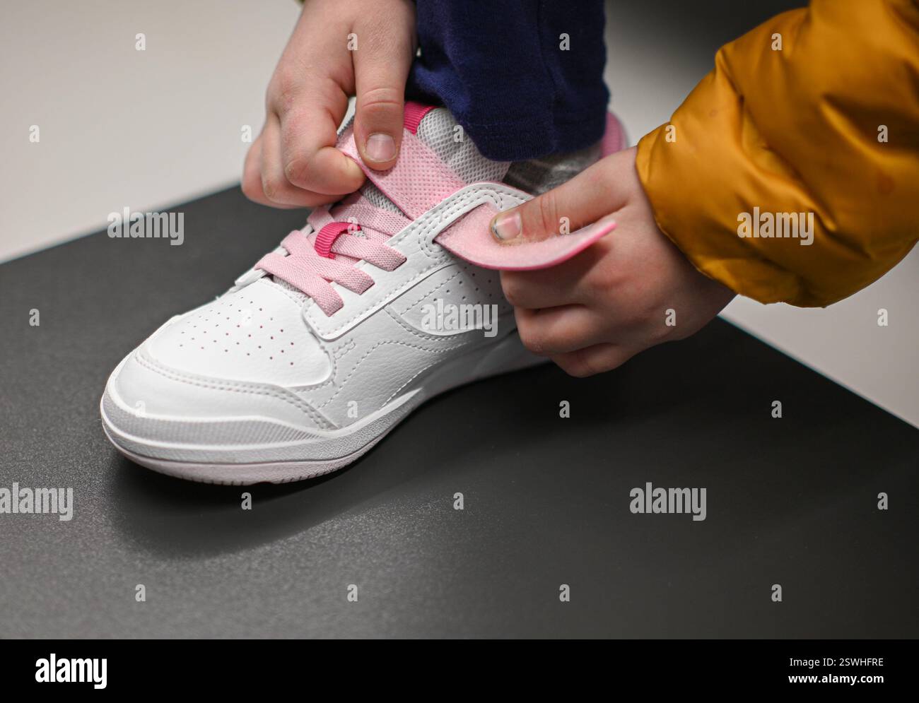Close-up of hands fastening velcro strap on child's white shoe with ...