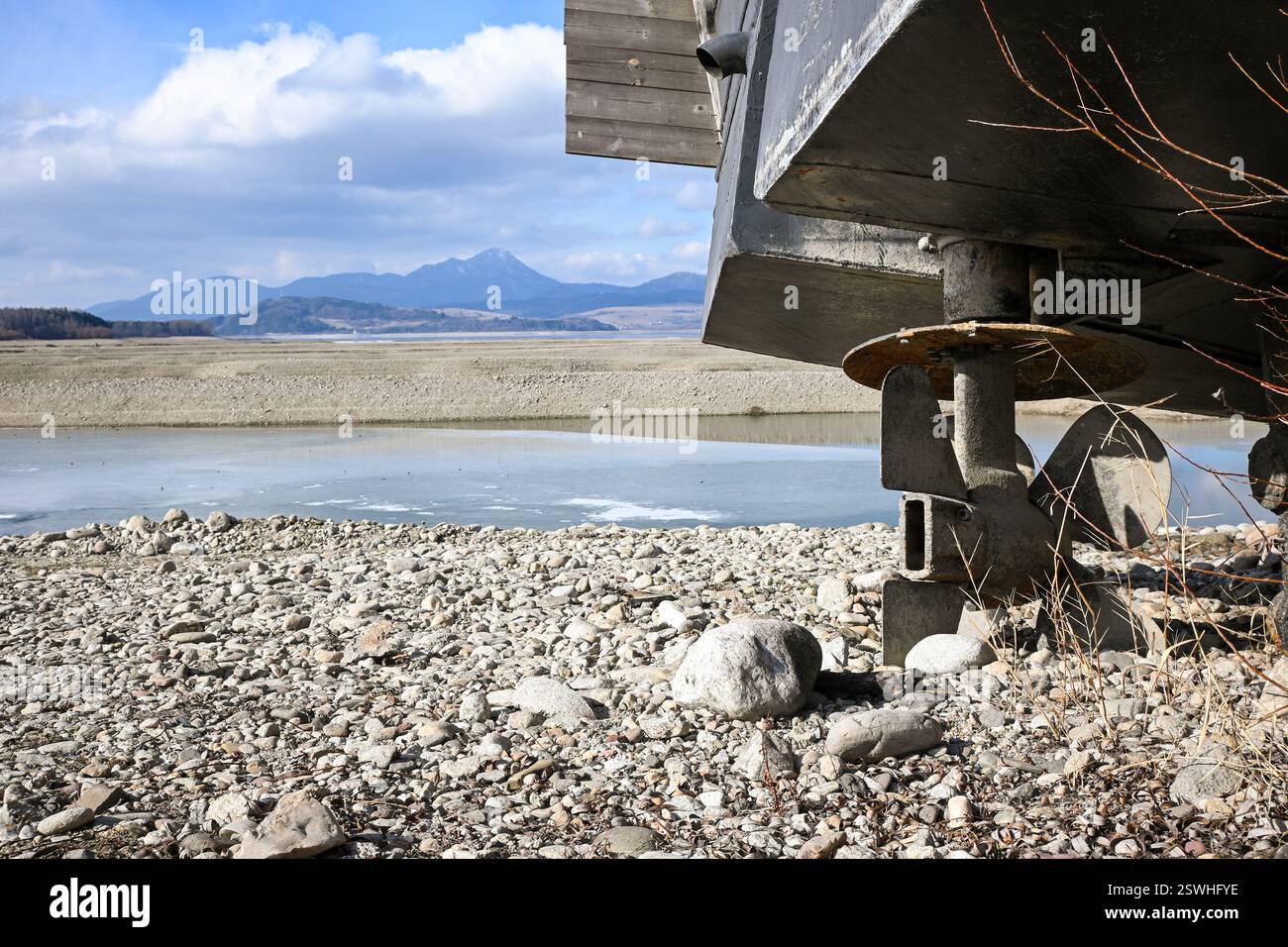 Stranded boat on a dry lake bed with mountains in the background ...