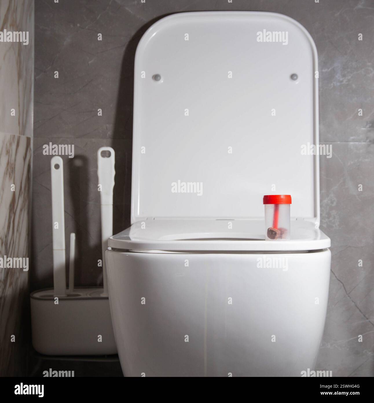 Sterile container with stool test on the toilet bowl in the toilet ...