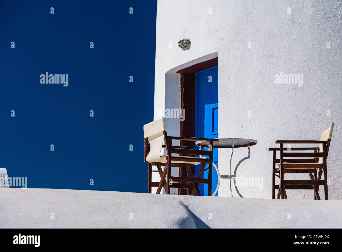 A building with white walls and blue doors in Oia, Santorini, Greece ...