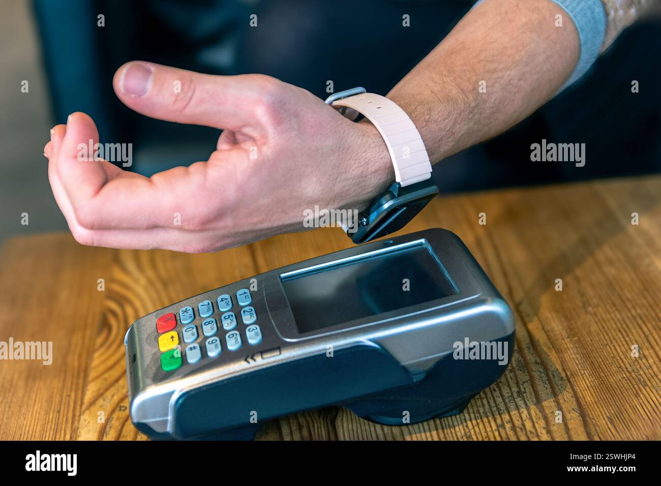 Man using a smartwatch for contactless payment at a payment terminal ...