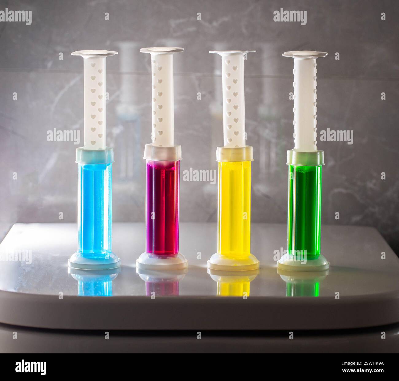 A set of multi-colored syringes with different scents on the toilet ...