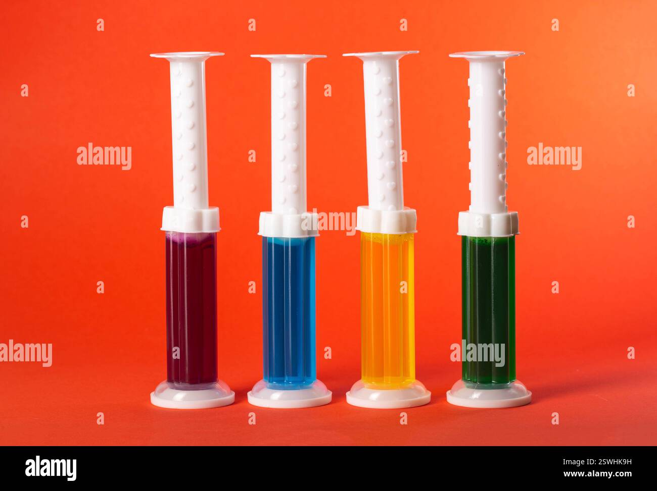 Set of multi-colored syringes with cleaning disinfectant gel on a red ...