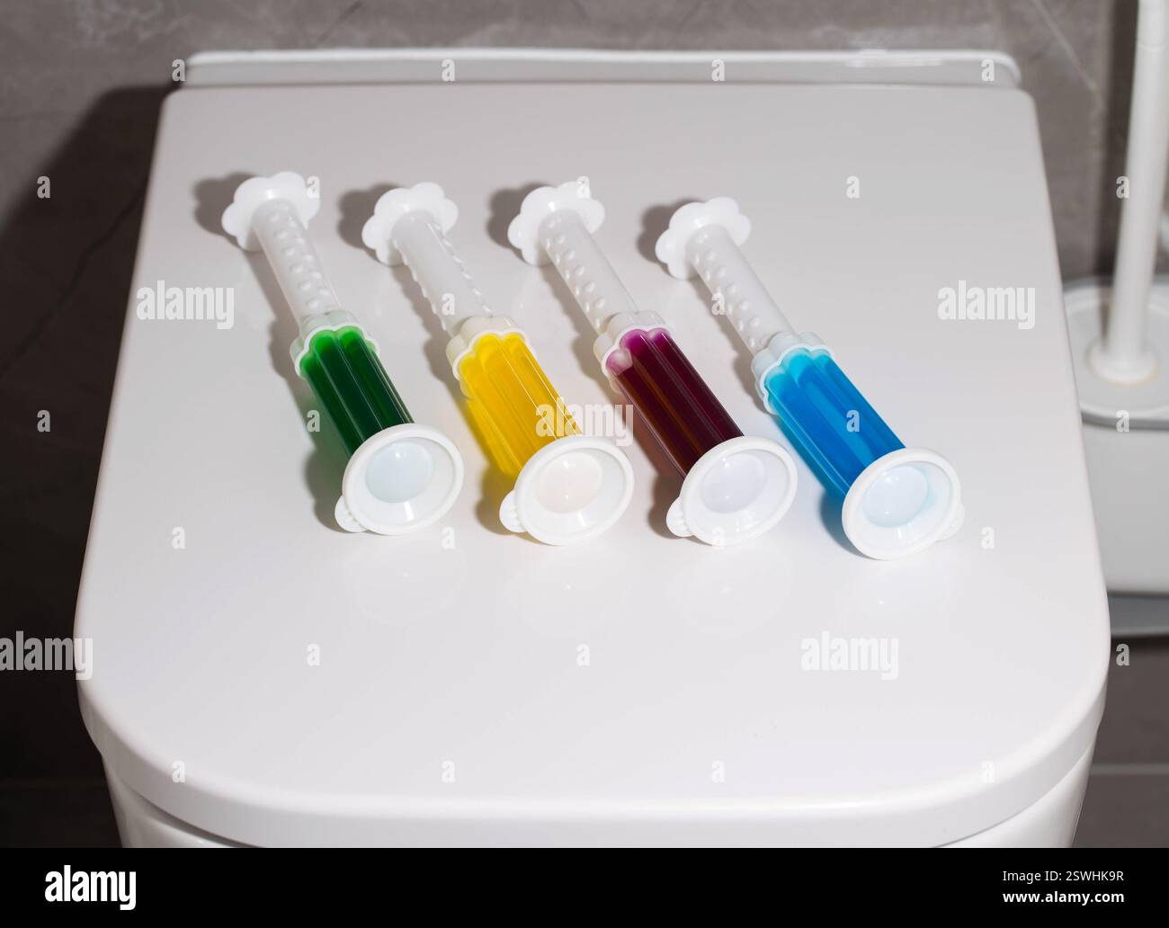 A set of multi-colored syringes with different scents on the toilet ...