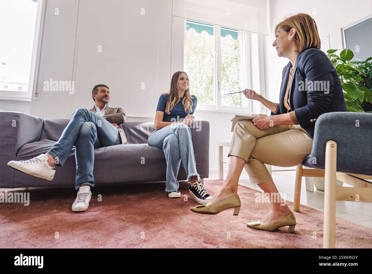 A therapist leading a group therapy session with two middle-aged ...