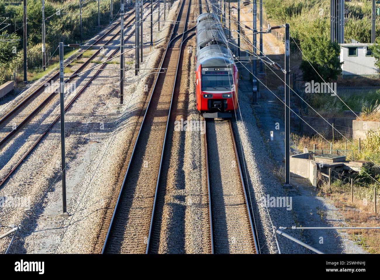 Red and grey modern train moving along the railroad in portugal ...