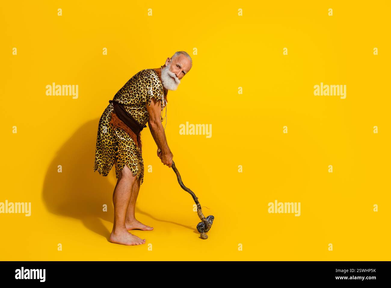Photo of focused caveman play golf with rock tool club wear animal skin ...